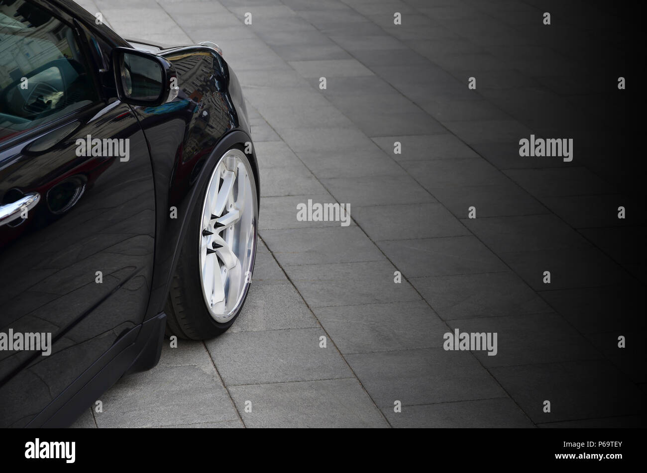 Diagonal view of a black glossy car with white wheels, which stands on ...