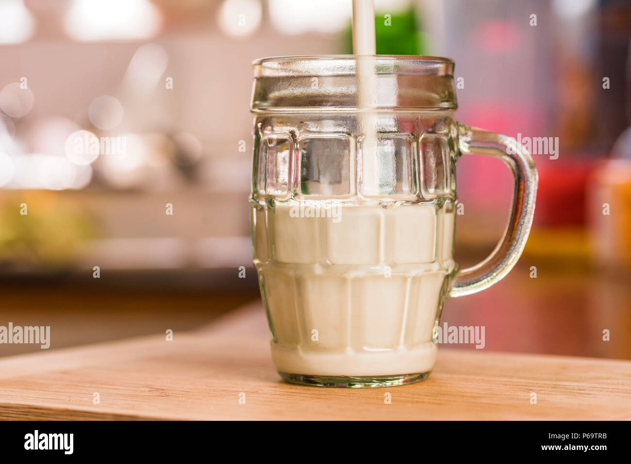 Closeup view pouring fresh kefir probiotik drink into half full clear ...