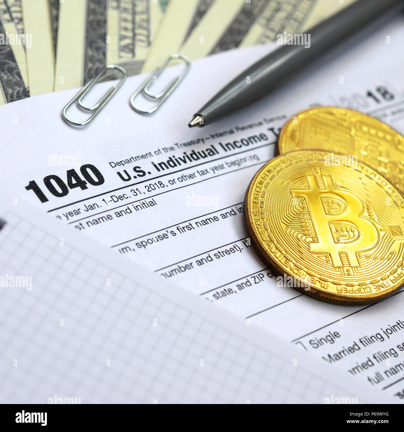 The pen, bitcoins and dollar bills is lies on the tax form 1040 U.S ...