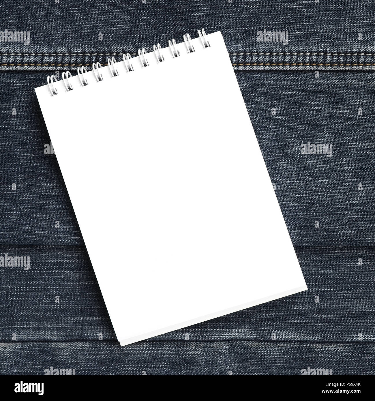 White notebook with clean pages lying on dark blue jeans background ...