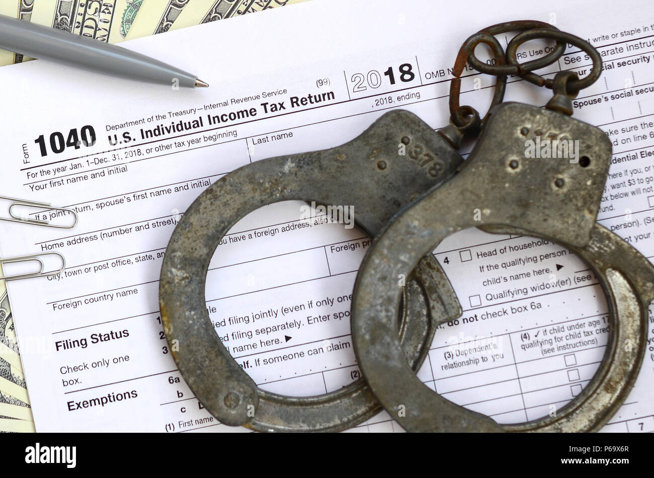 Police handcuffs lie on the tax form 1040. The concept of problems with ...