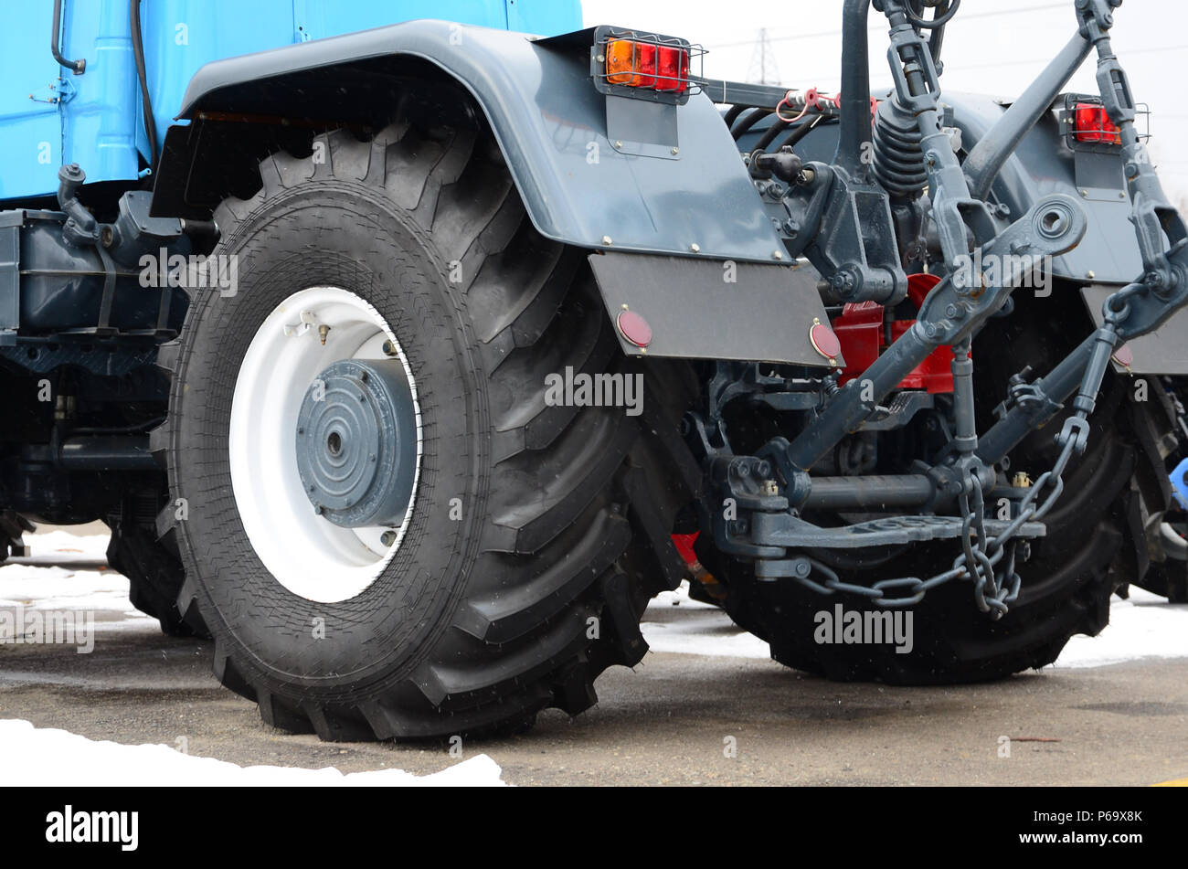 Wheels of back view of new tractor in snowy weather. Agricultural ...