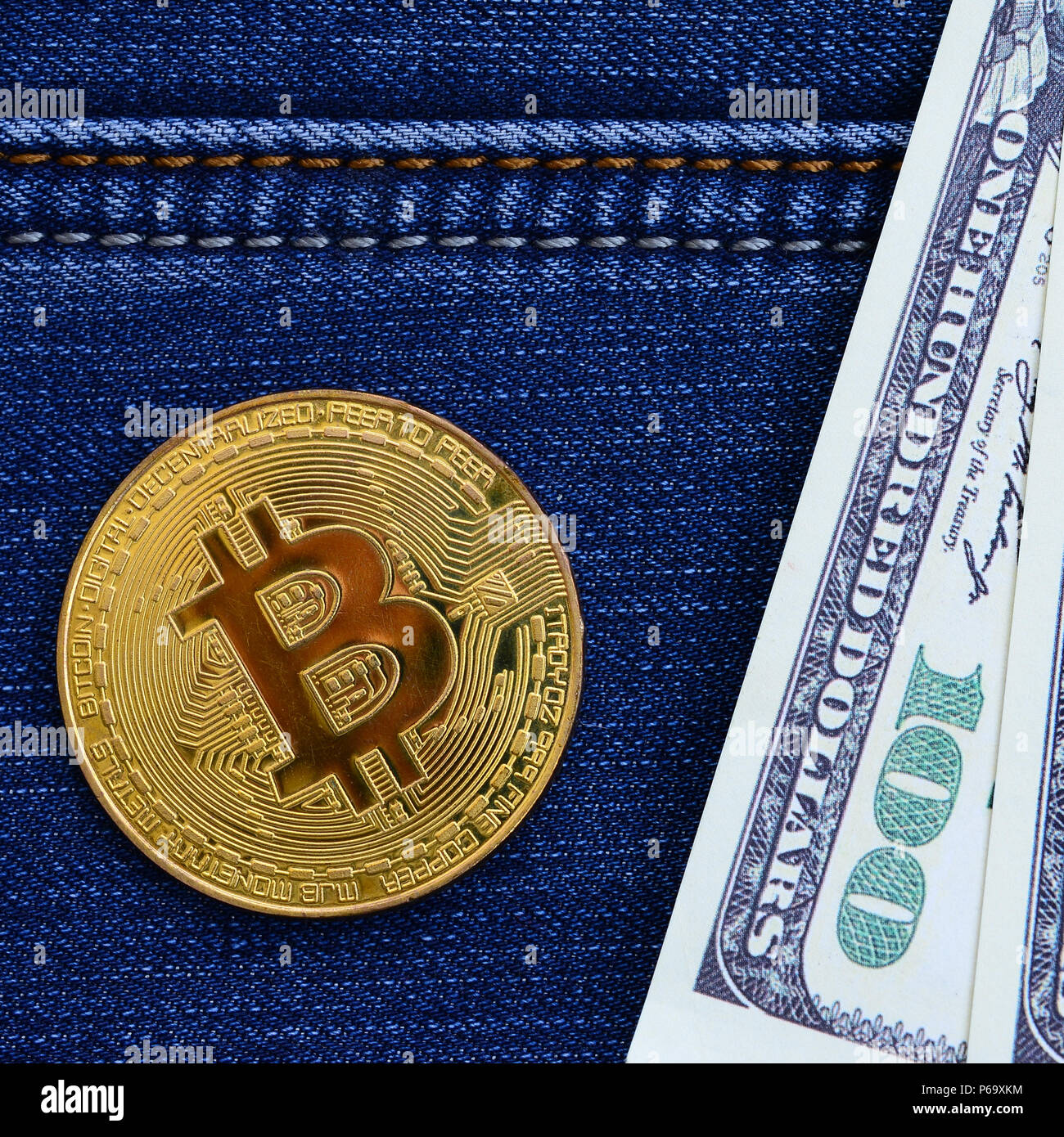 Golden Bitcoin and dollar bills lies on a blue jeans fabric. New ...