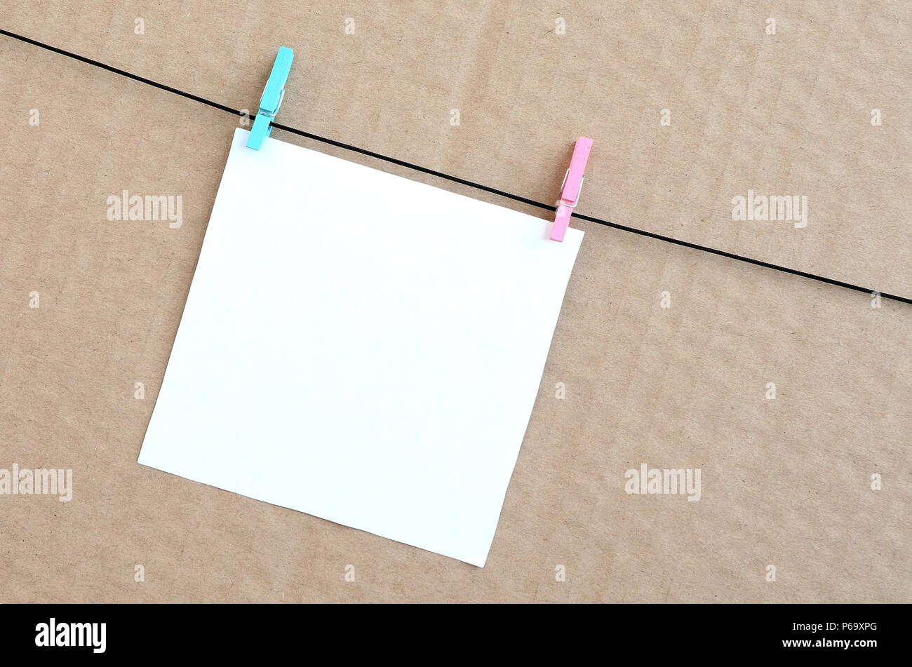 White blank card on rope on a brown cardboard background. Creative ...