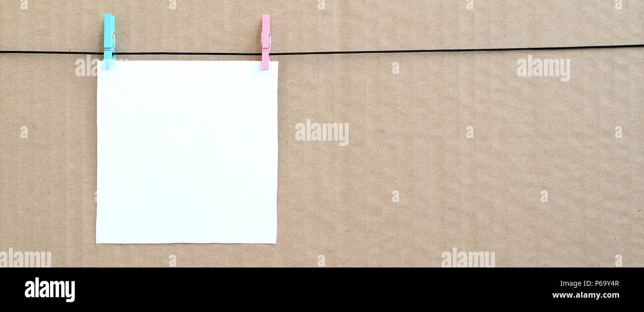 White blank card on rope on a brown cardboard background. Creative ...