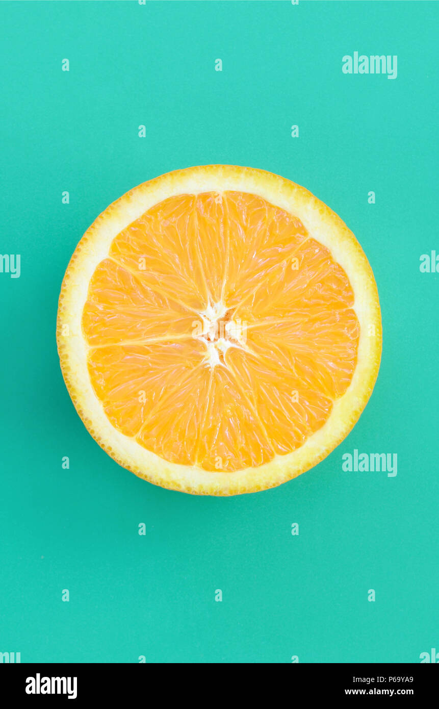 Top view of a one orange fruit slice on bright background in turquoise ...