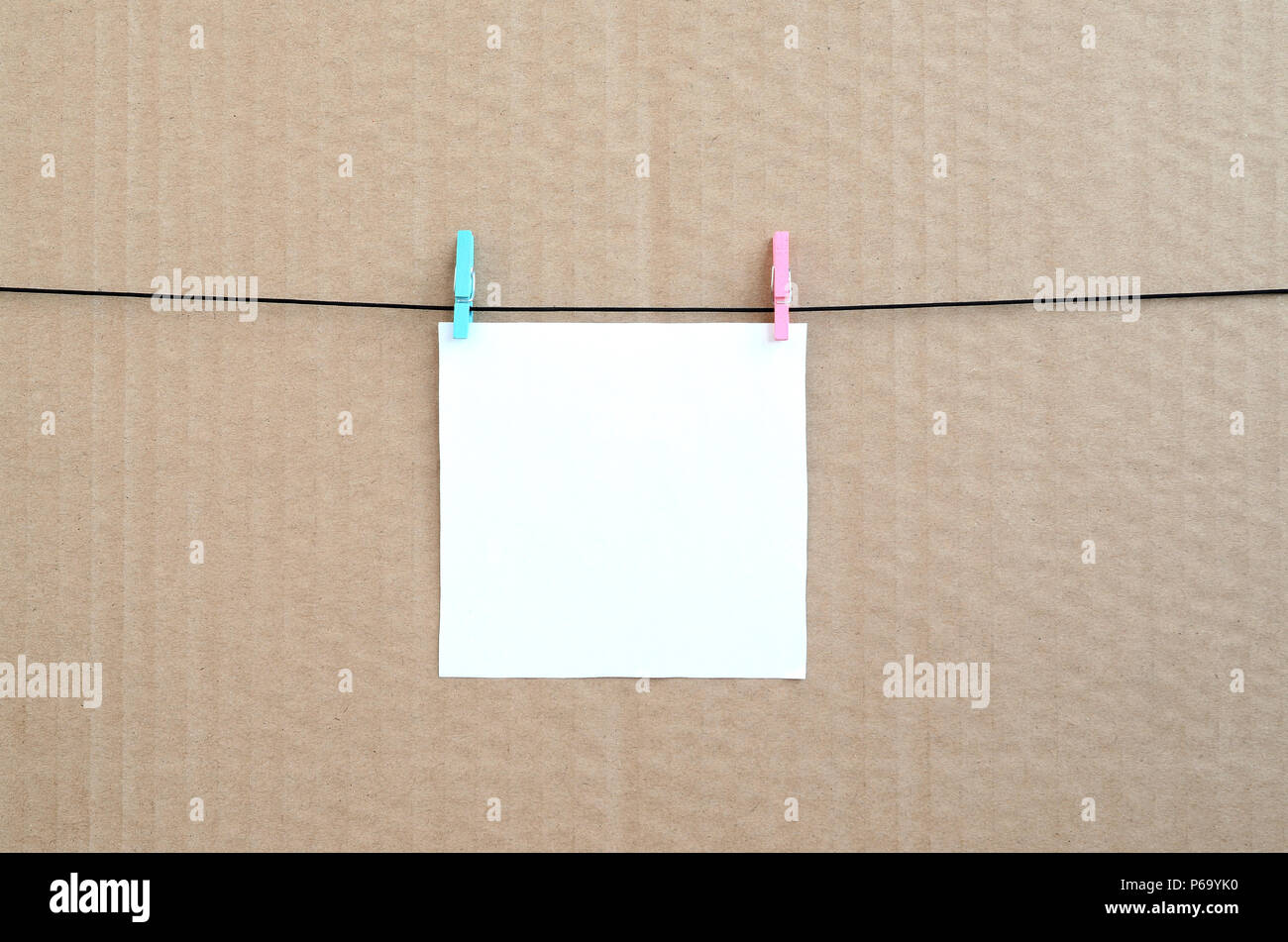 White blank card on rope on a brown cardboard background. Creative ...