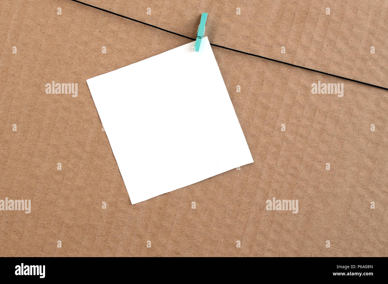 White blank card on rope on a brown cardboard background. Creative ...