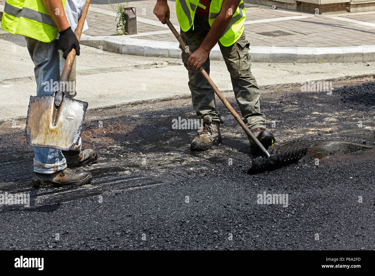 Workers using asphalt paver tools during road construction Stock Photo ...