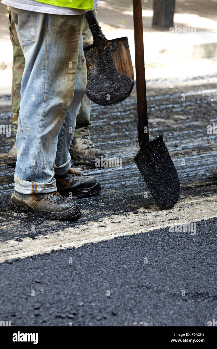 Workers using asphalt paver tools during road construction Stock Photo ...