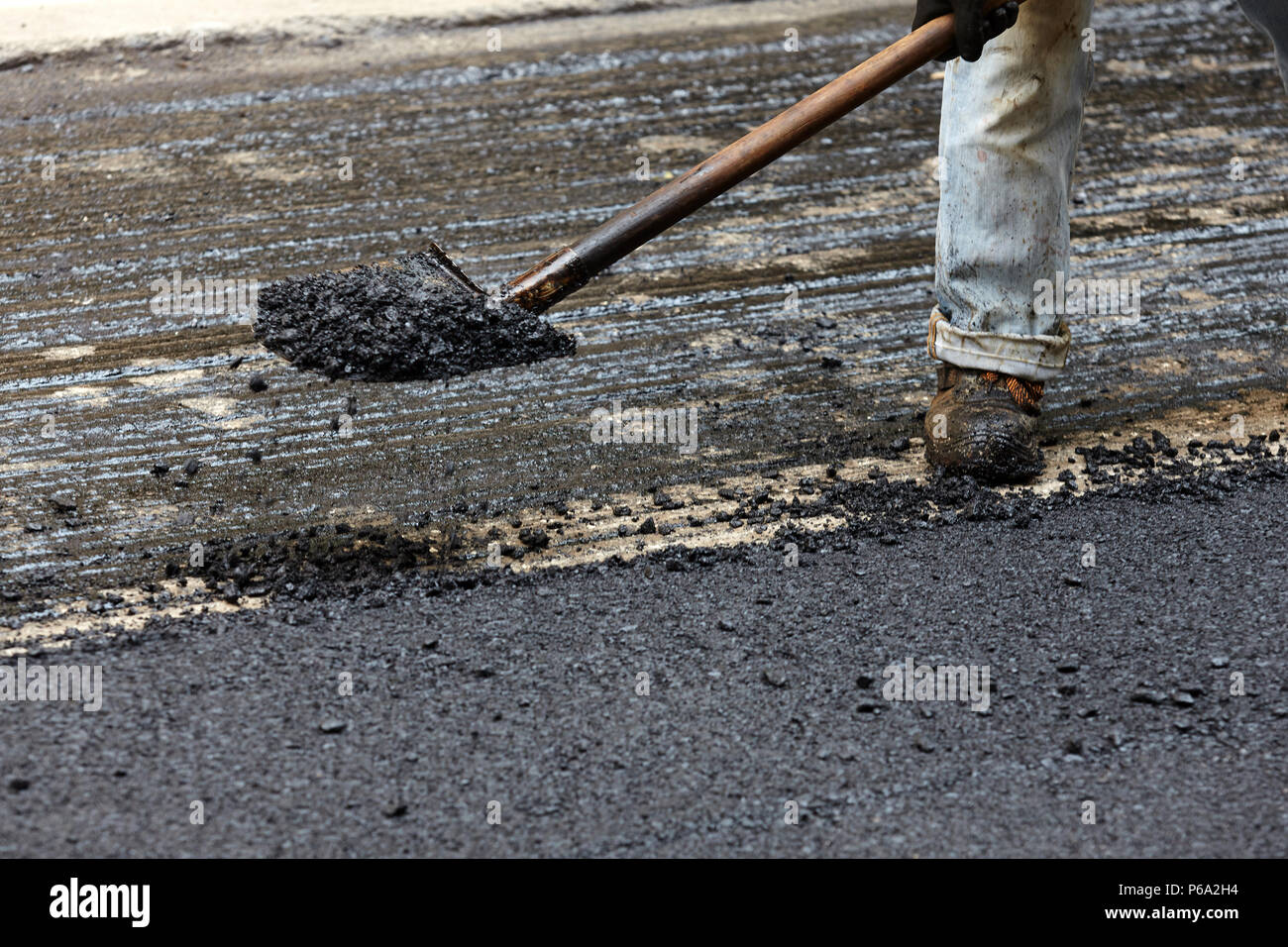 Worker using asphalt paver tool during road construction Stock Photo ...