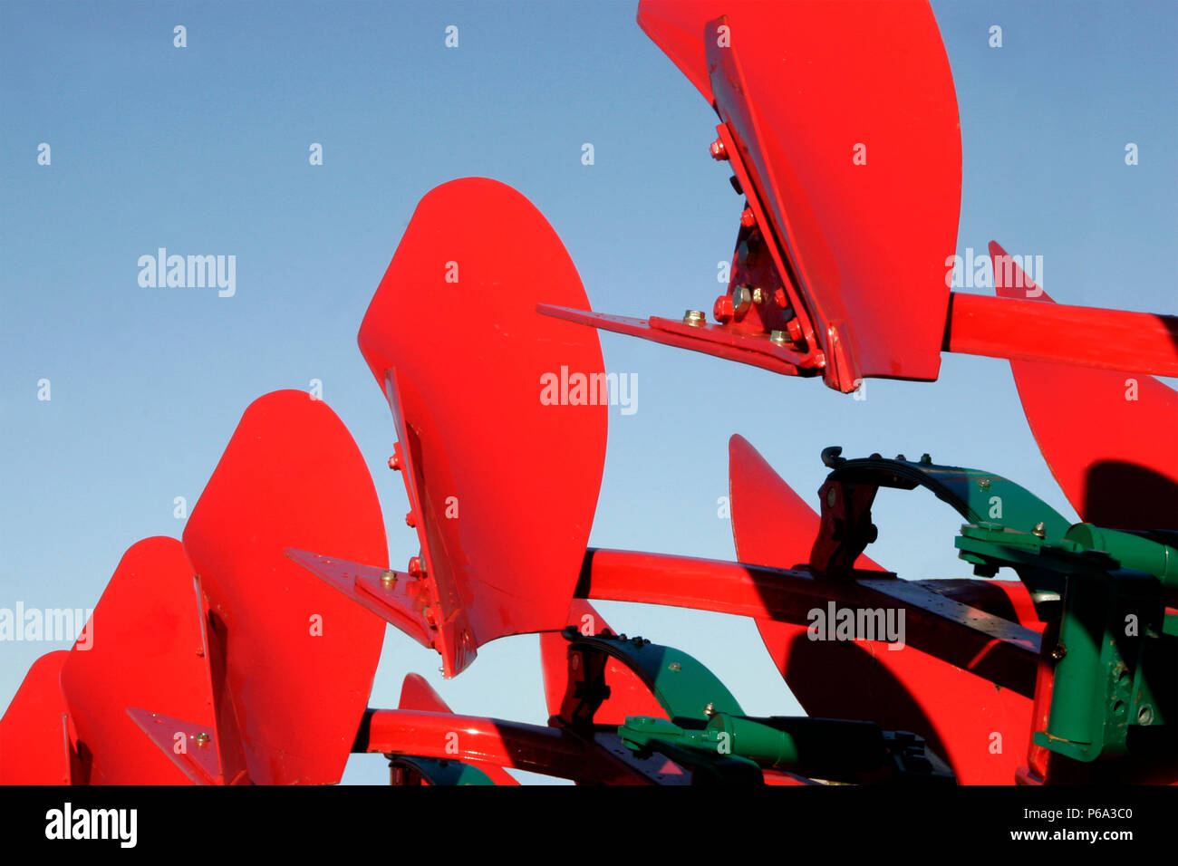 A line of red metal plows ready for work Stock Photo - Alamy