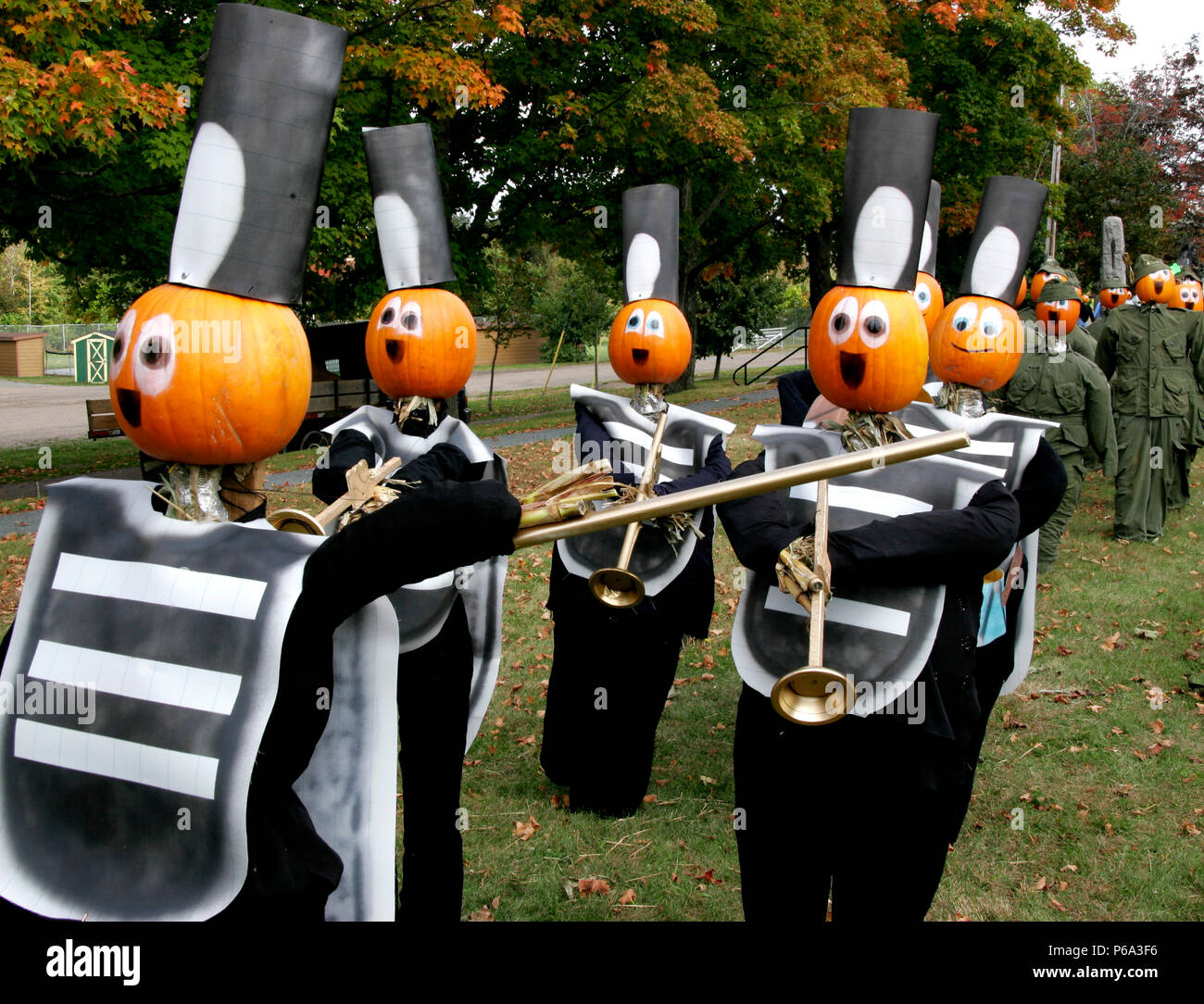 A group of pumpkins are dressed up with faces playing in a marching ...