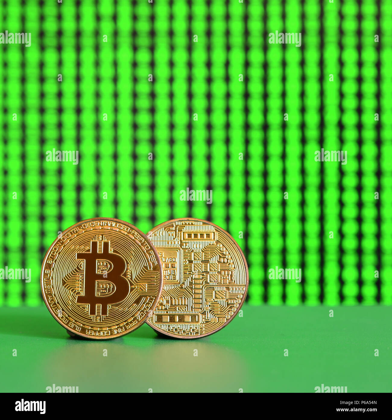 Two gold bitcoins lie on the green surface on the background of the ...