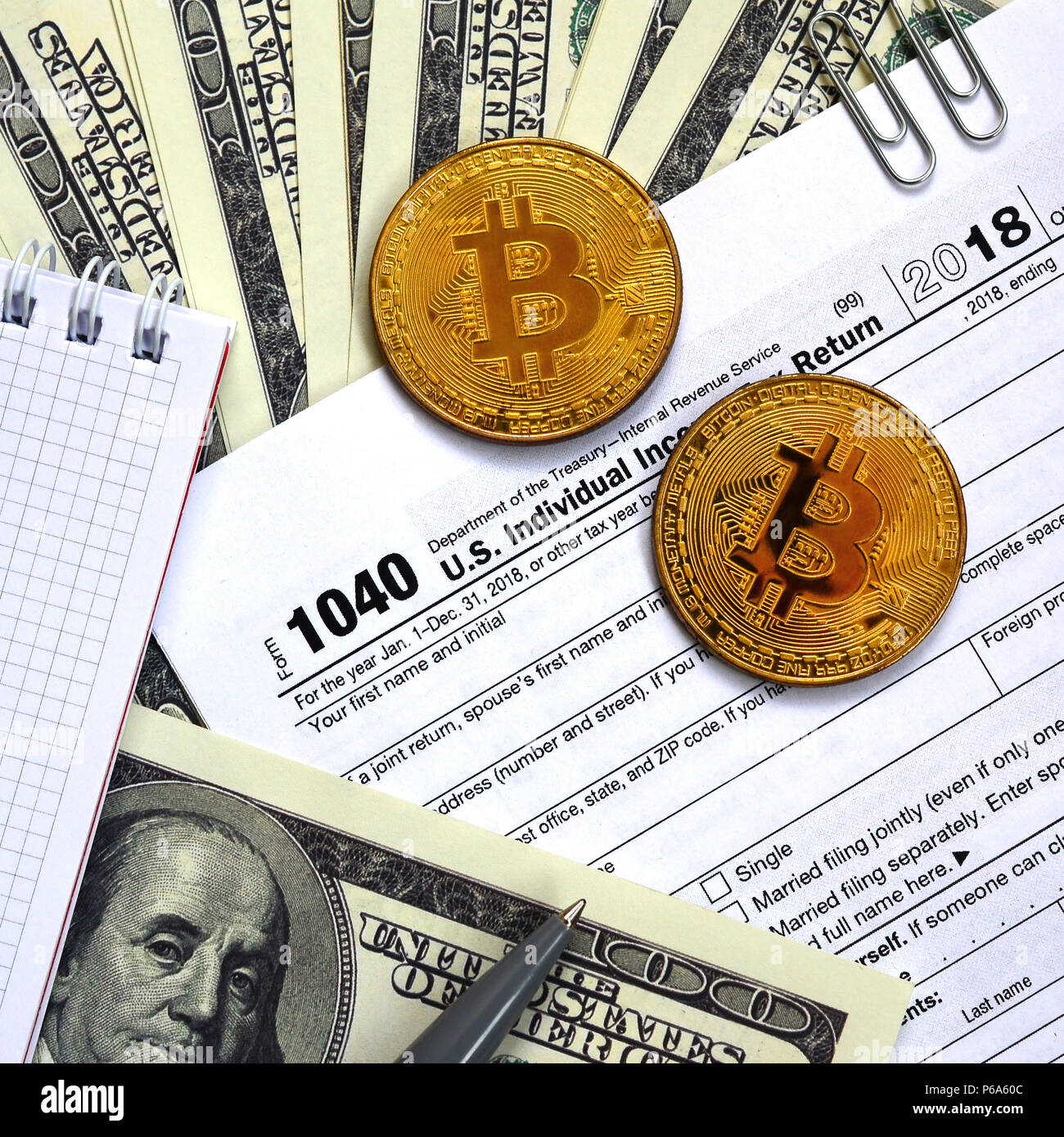 The pen, bitcoins and dollar bills is lies on the tax form 1040 U.S ...