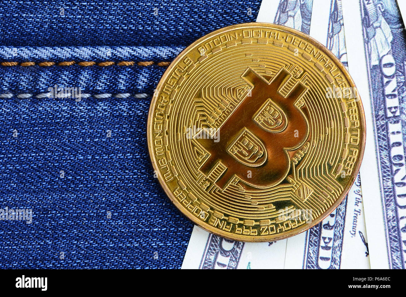 Golden Bitcoin and dollar bills lies on a blue jeans fabric. New ...