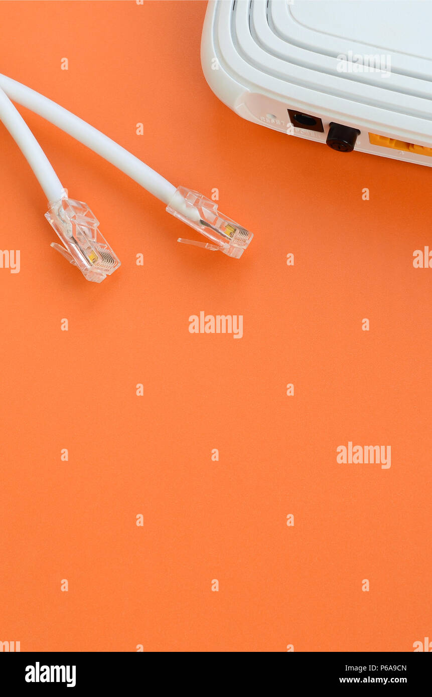Internet router and Internet cable plugs lie on a bright orange ...