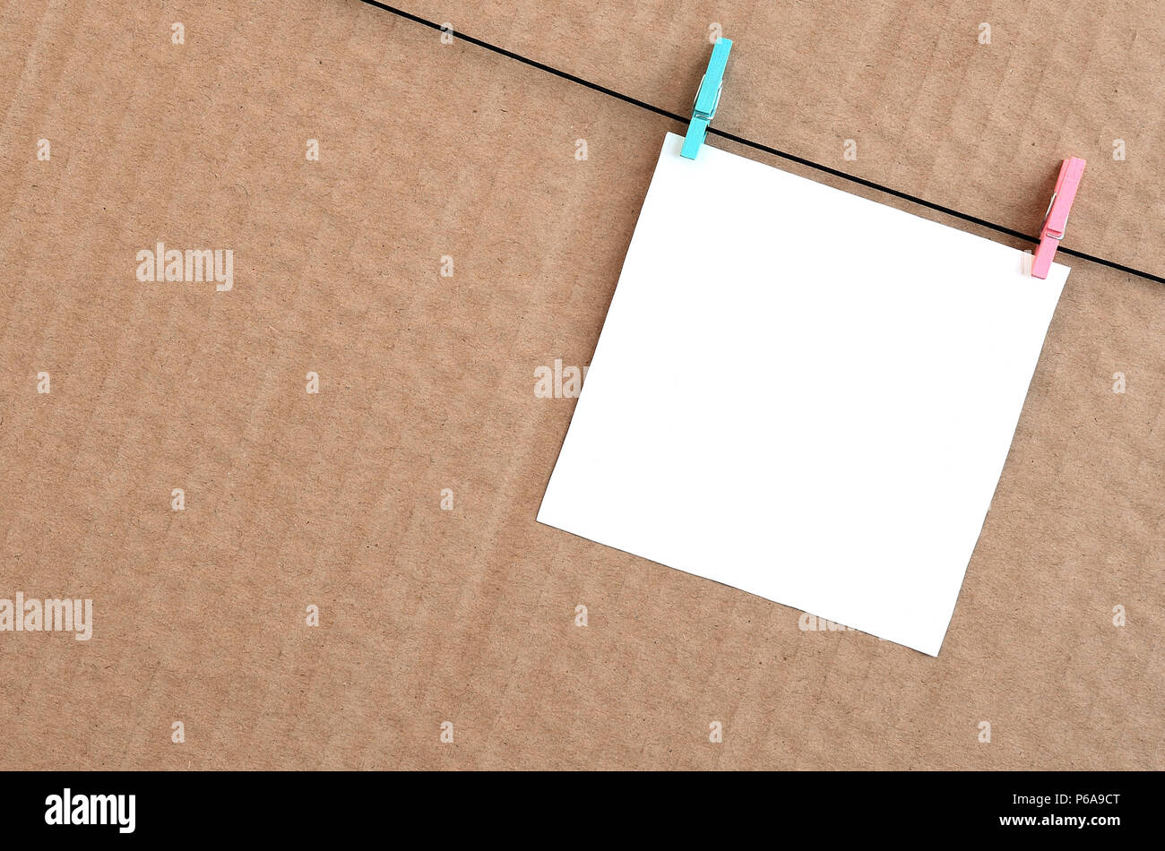 White blank card on rope on a brown cardboard background. Creative ...