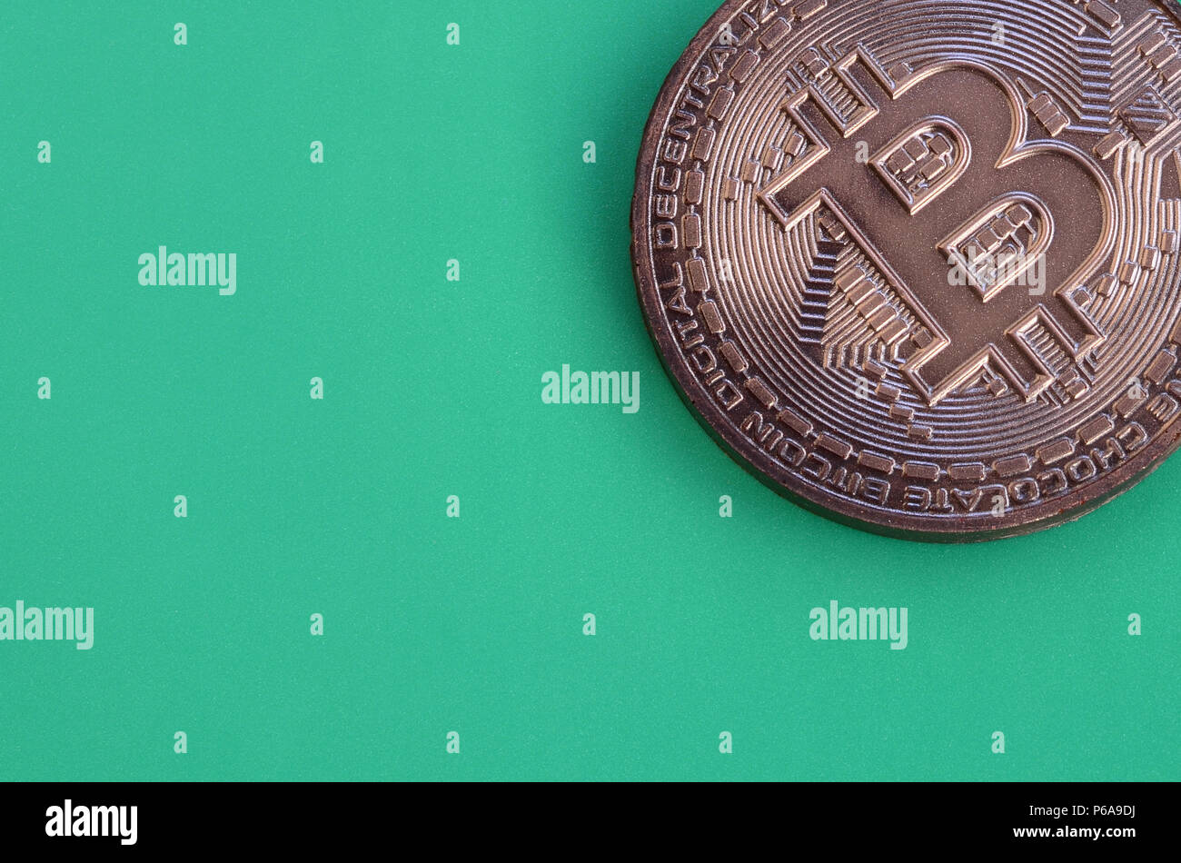 Chocolate product in the form of physical bitcoin lies on a green ...