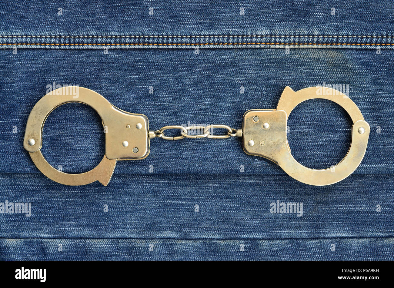 Police steel handcuffs lying on dark blue jeans background Stock Photo ...