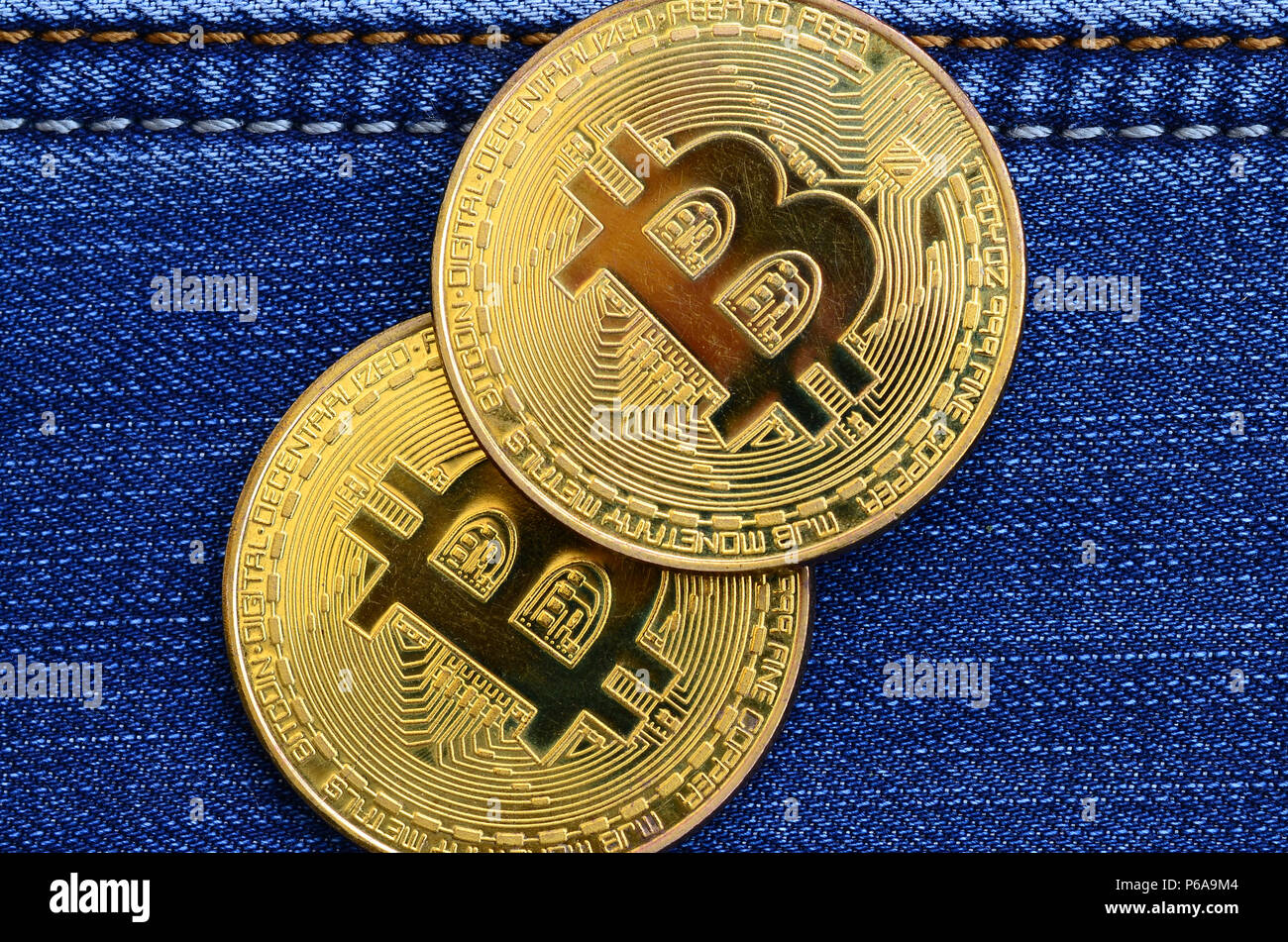 Two golden Bitcoins is lies on a blue jeans fabric. New virtual money ...