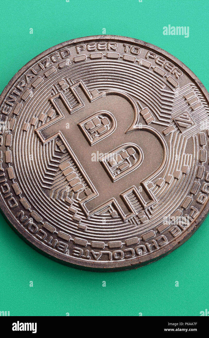 Chocolate product in the form of physical bitcoin lies on a green ...
