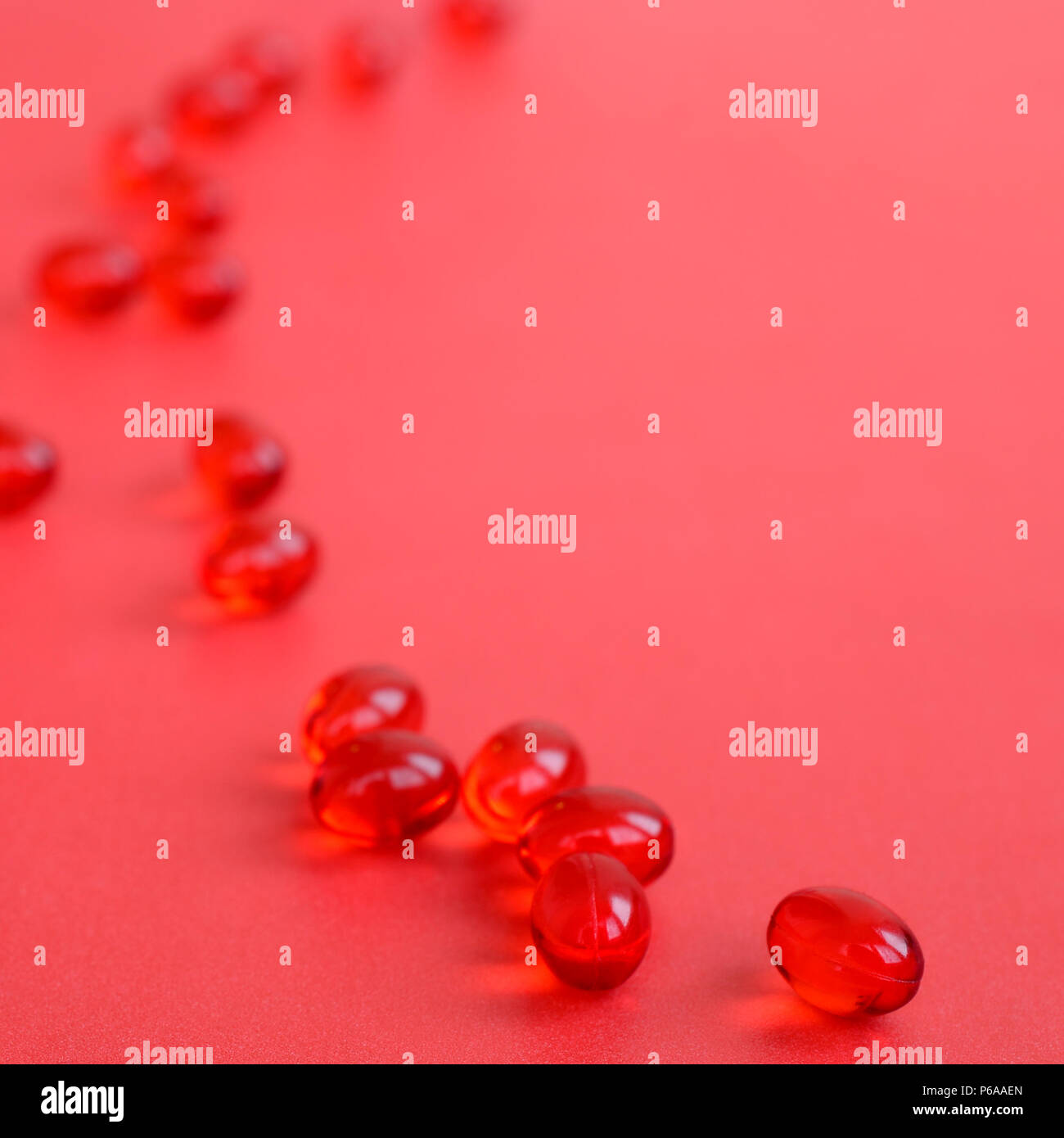 A lot of transparent red tablets lie on the red surface Stock Photo - Alamy