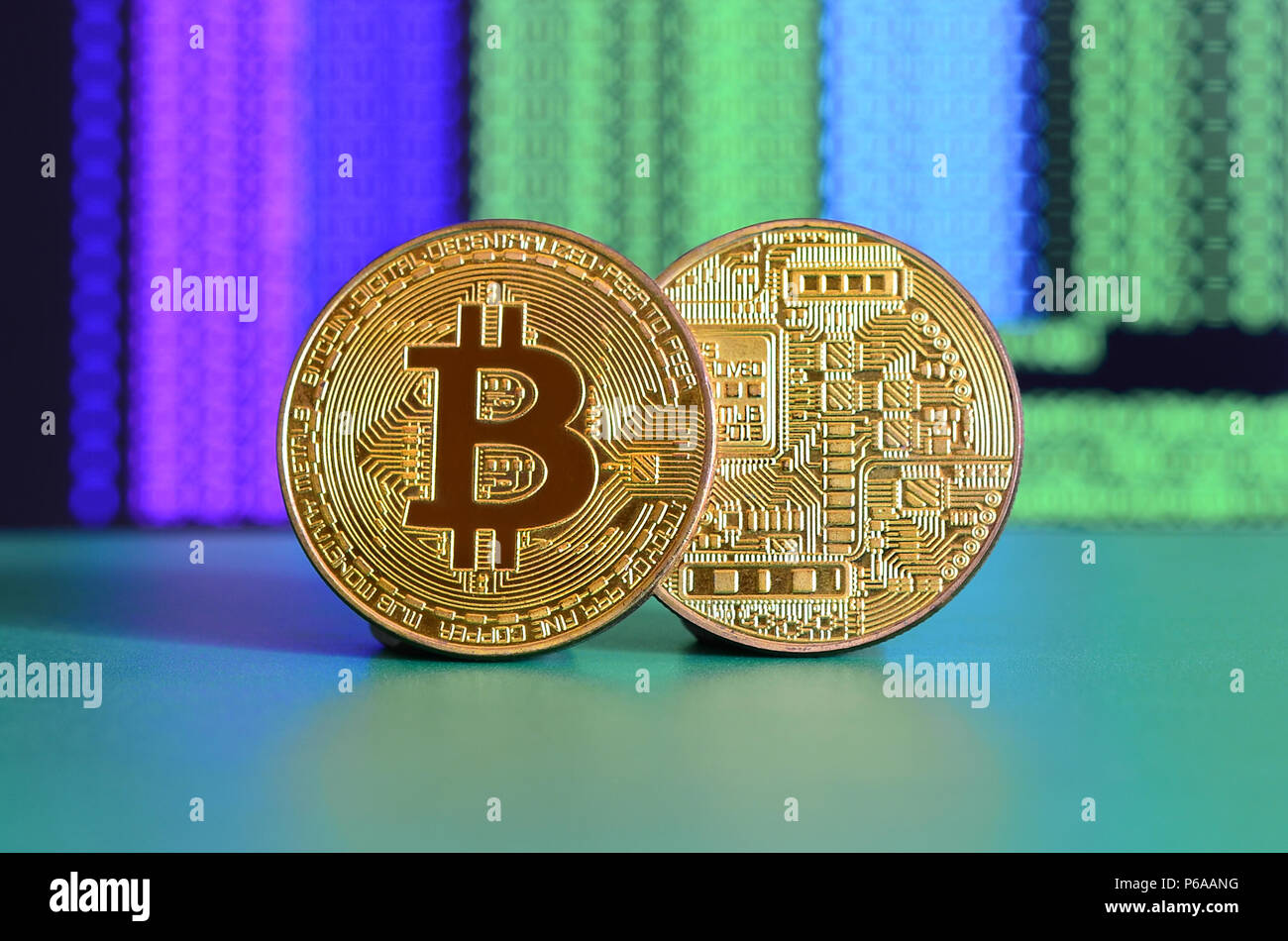 Two gold bitcoins lie on the green surface on the background of the ...
