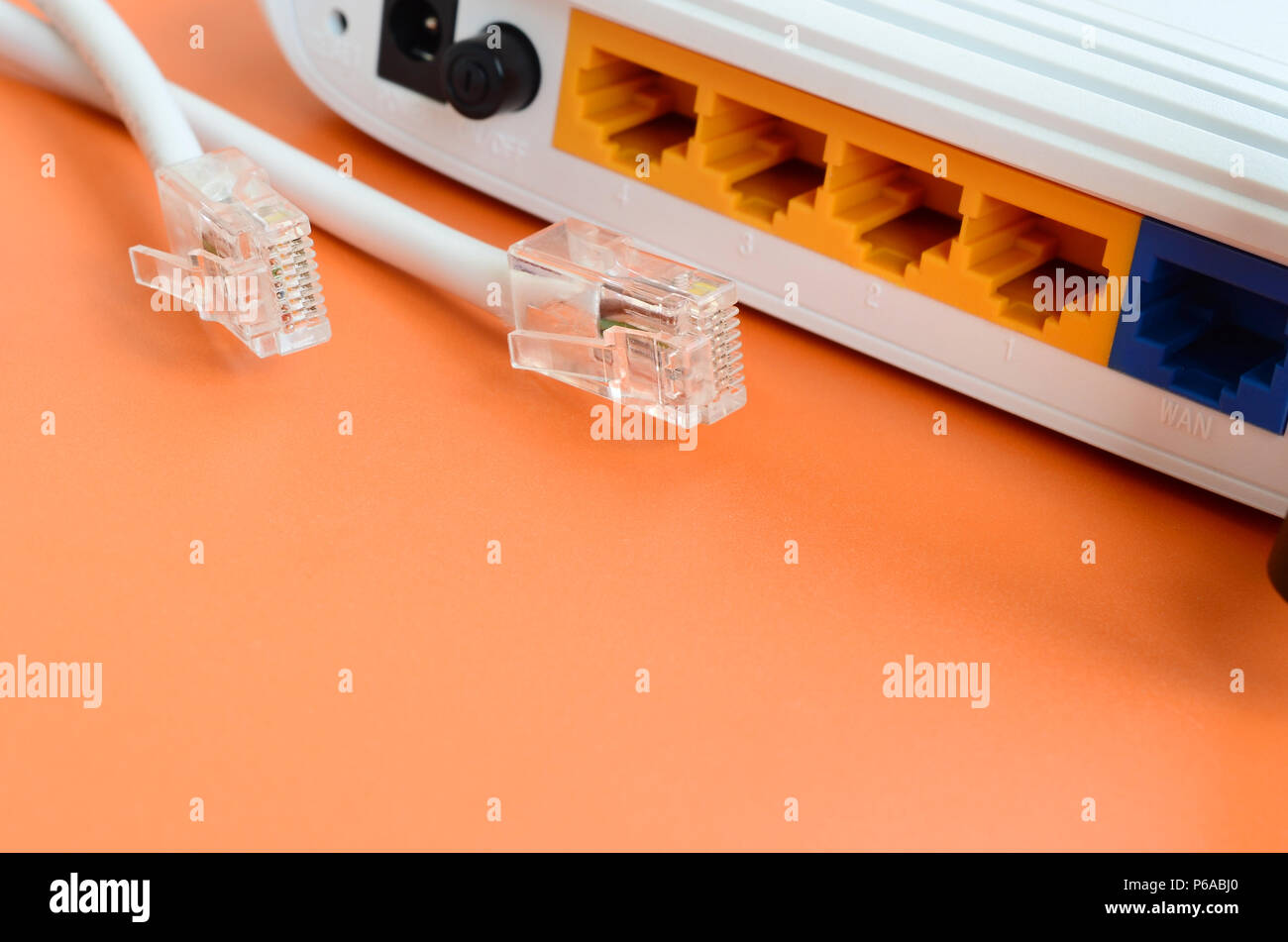 Internet router and Internet cable plugs lie on a bright orange ...