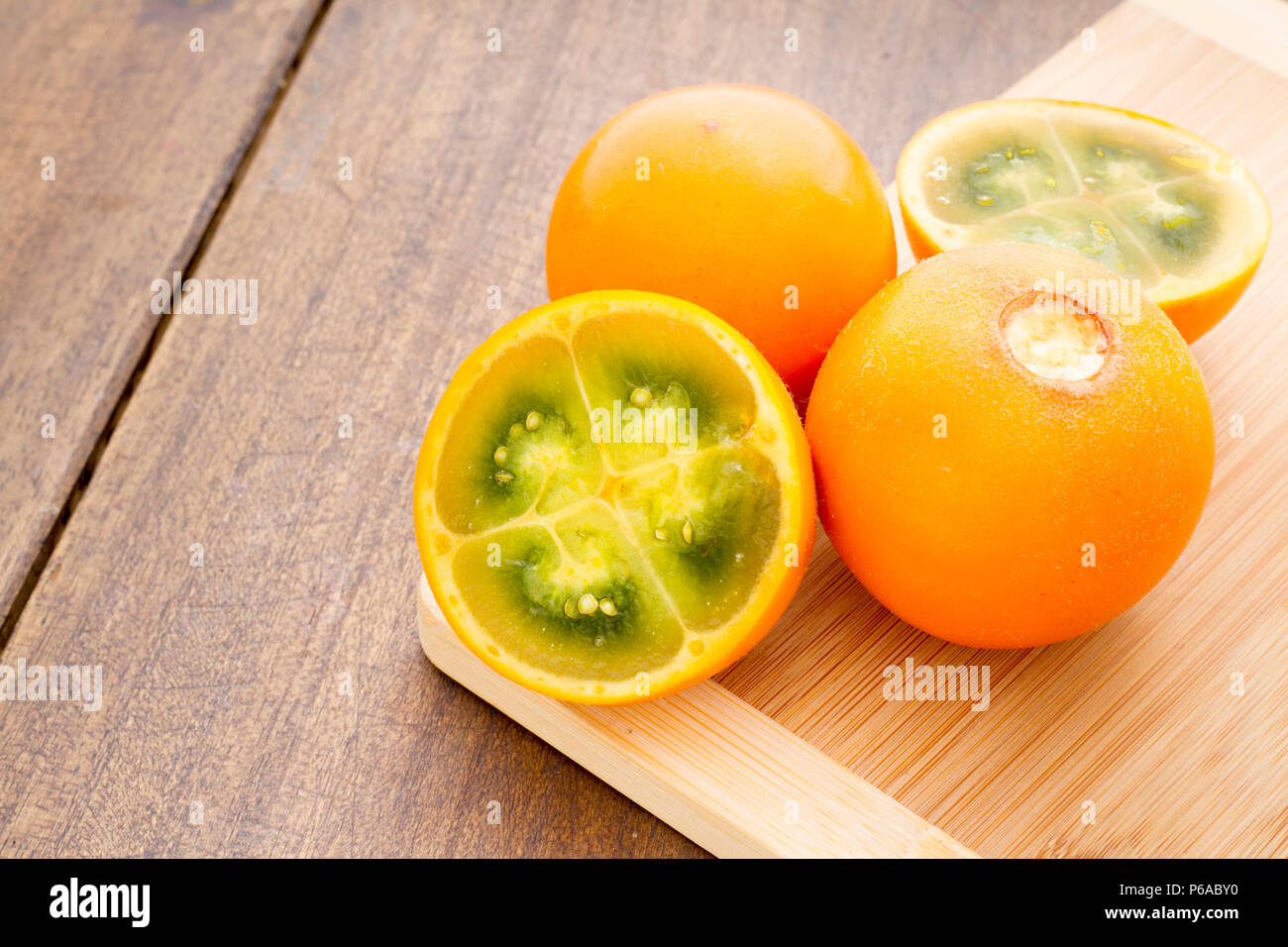 Fruits and slices of lulo or naranjilla on the wooden table - Solanum ...