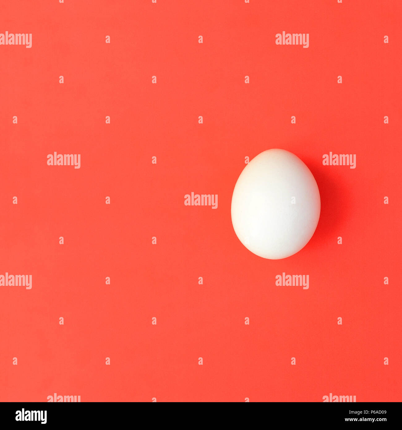 One white egg on a bright red background Stock Photo - Alamy
