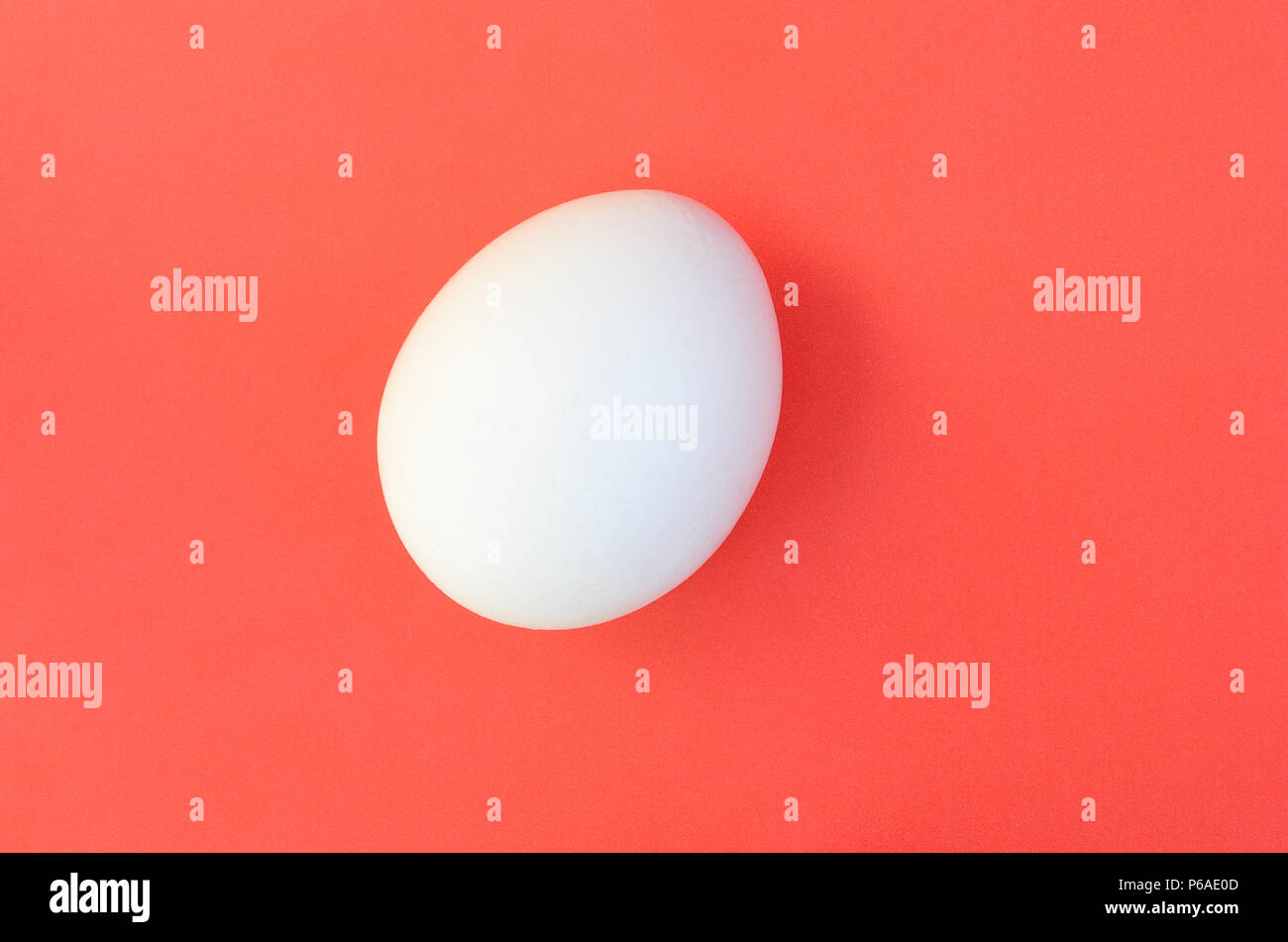One white egg on a bright red background Stock Photo - Alamy