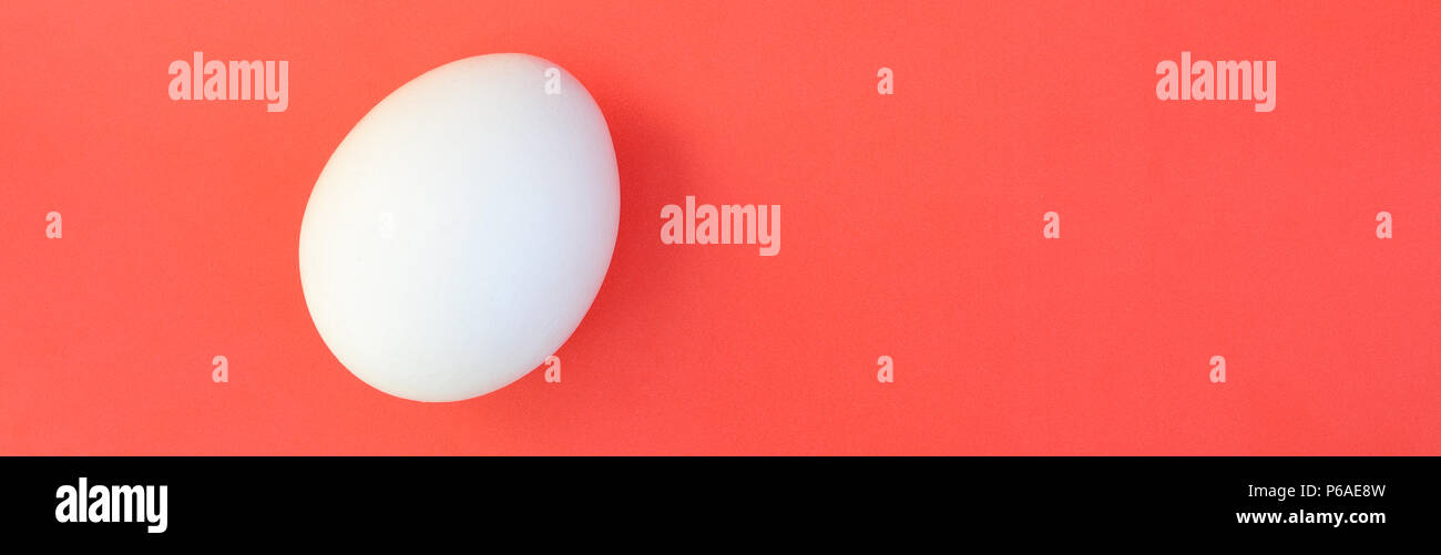One white egg on a bright red background Stock Photo - Alamy