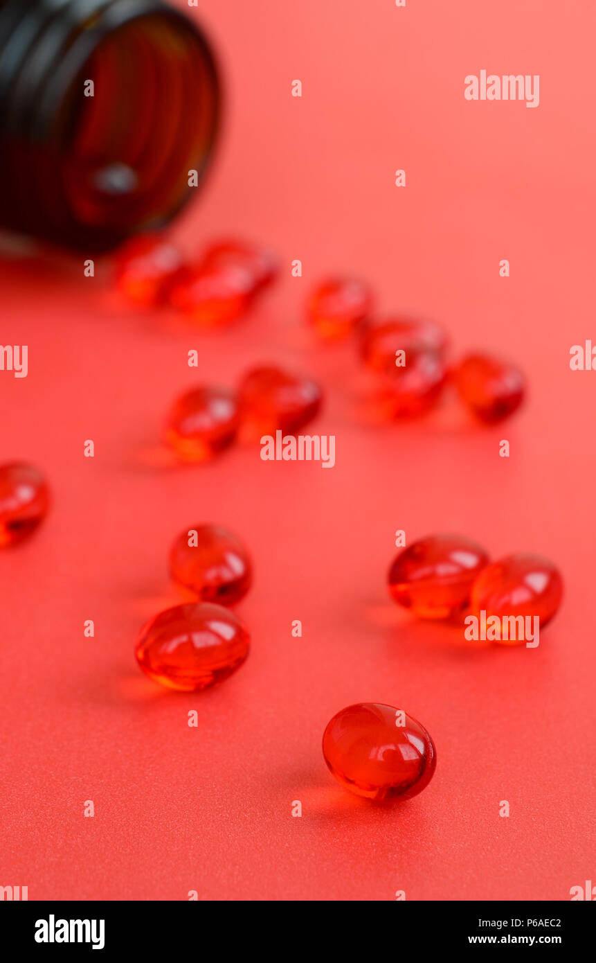 A lot of transparent red tablets were scattered from a small glass ...