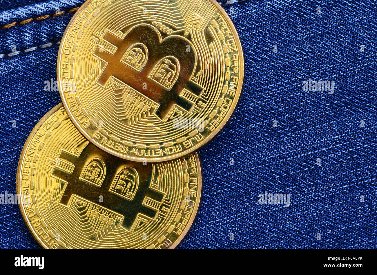 Two golden Bitcoins is lies on a blue jeans fabric. New virtual money ...
