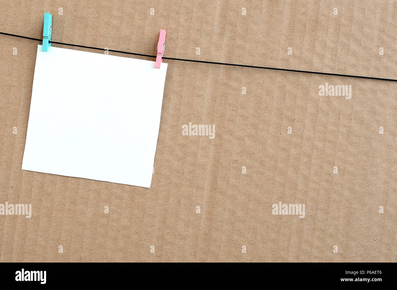 White blank card on rope on a brown cardboard background. Creative ...