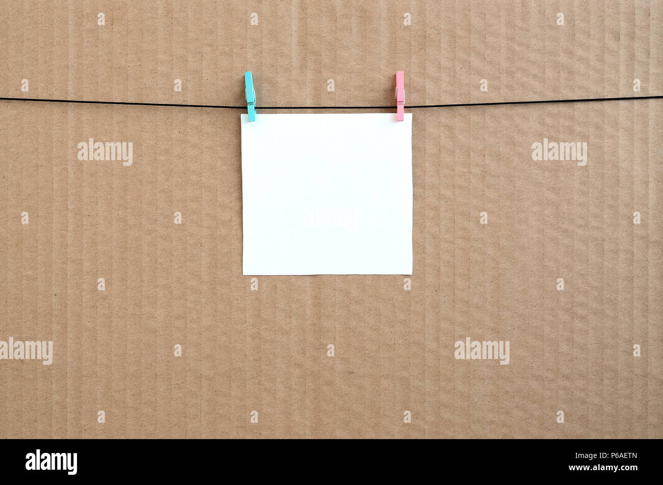 White blank card on rope on a brown cardboard background. Creative ...