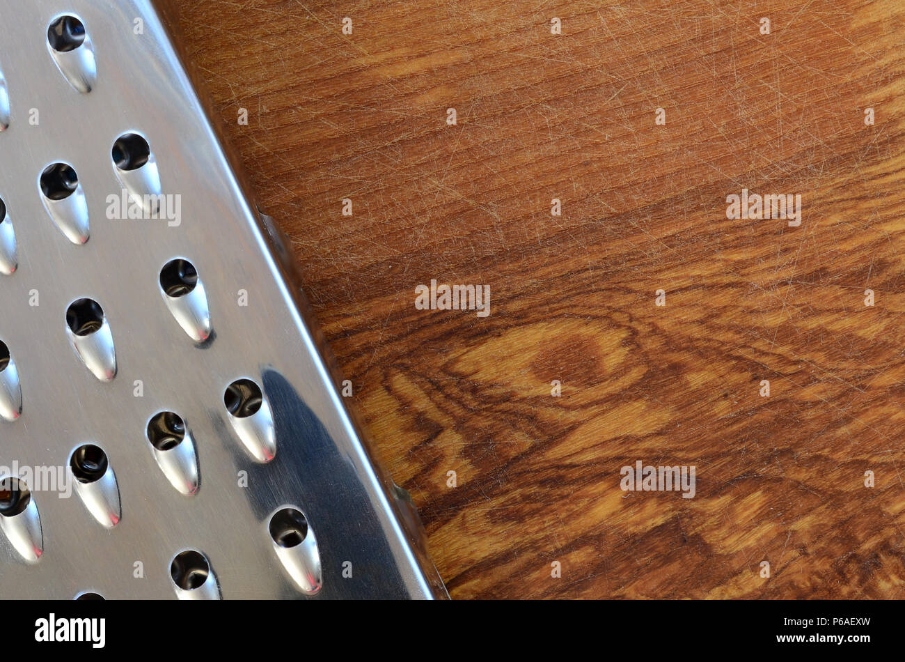 The chrome grater lies on the cutting board with a lot of scars from ...
