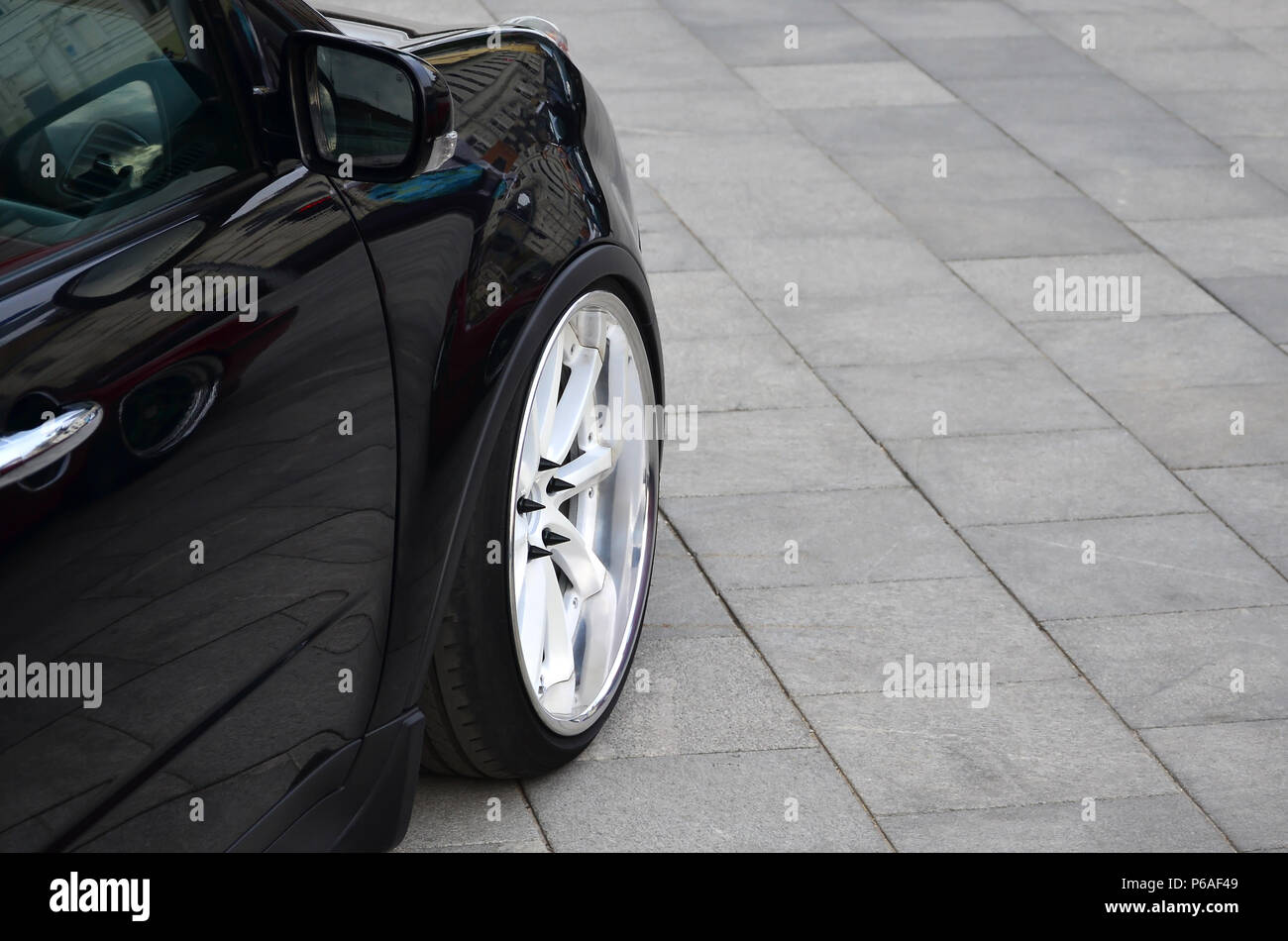 Diagonal view of a black glossy car with white wheels, which stands on ...