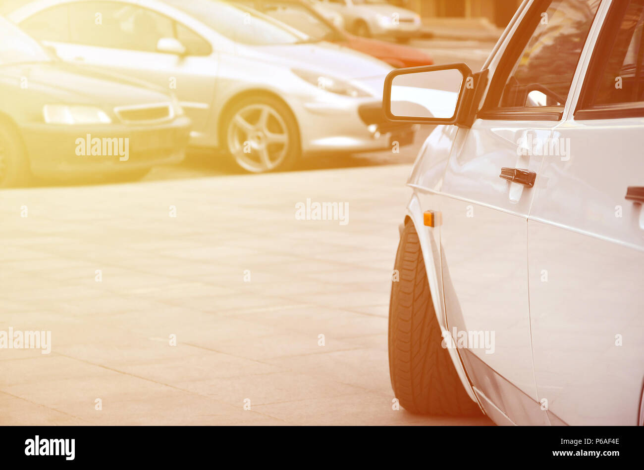 Diagonal view of a white glossy car that stands on a square of gray ...