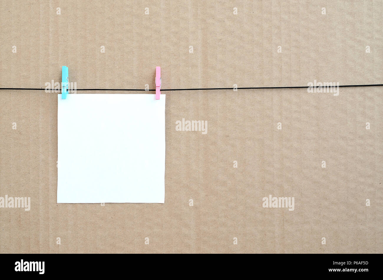 White blank card on rope on a brown cardboard background. Creative ...