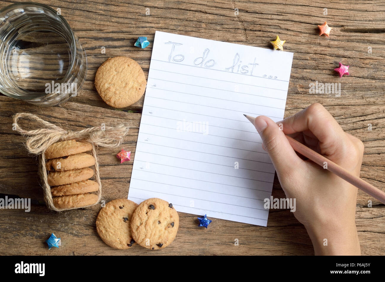 woman hand write to do list on wooden table with chocolate chip cookie ...