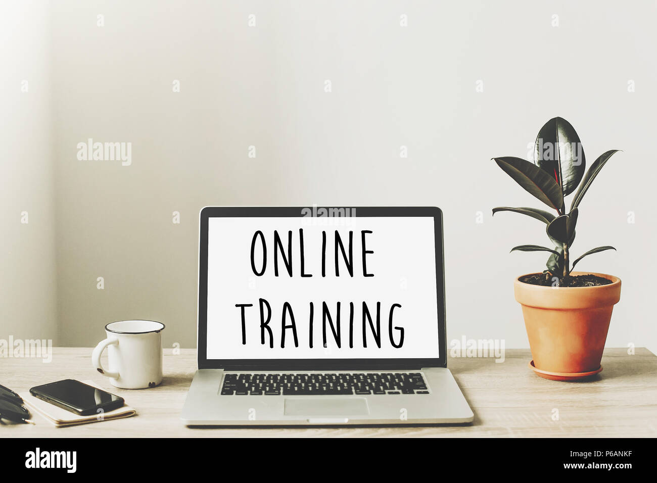 online training text on laptop screen on wooden desktop with phone ...