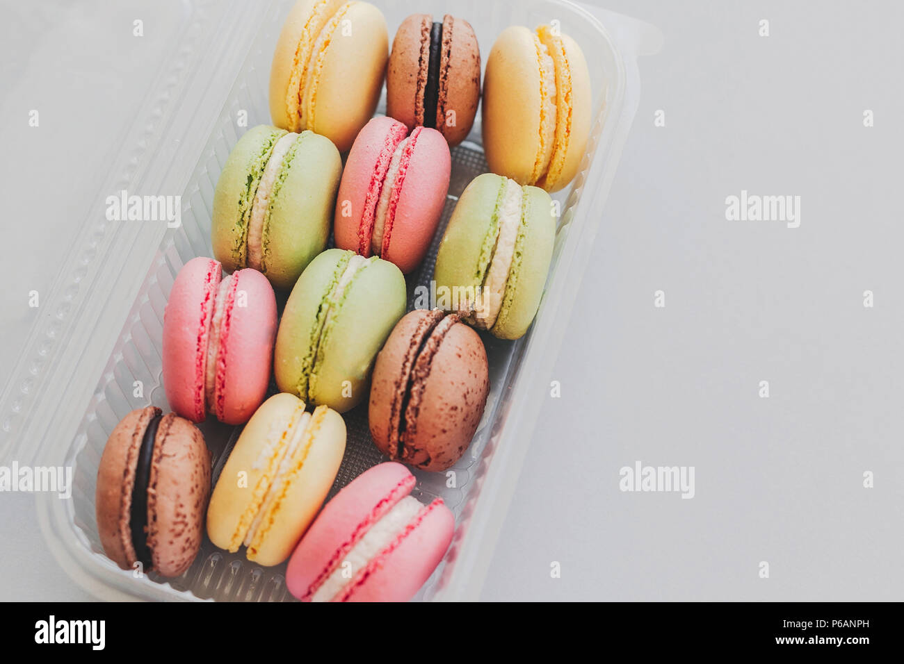 delicious colorful macaroons in plastic box on trendy pastel gray paper ...