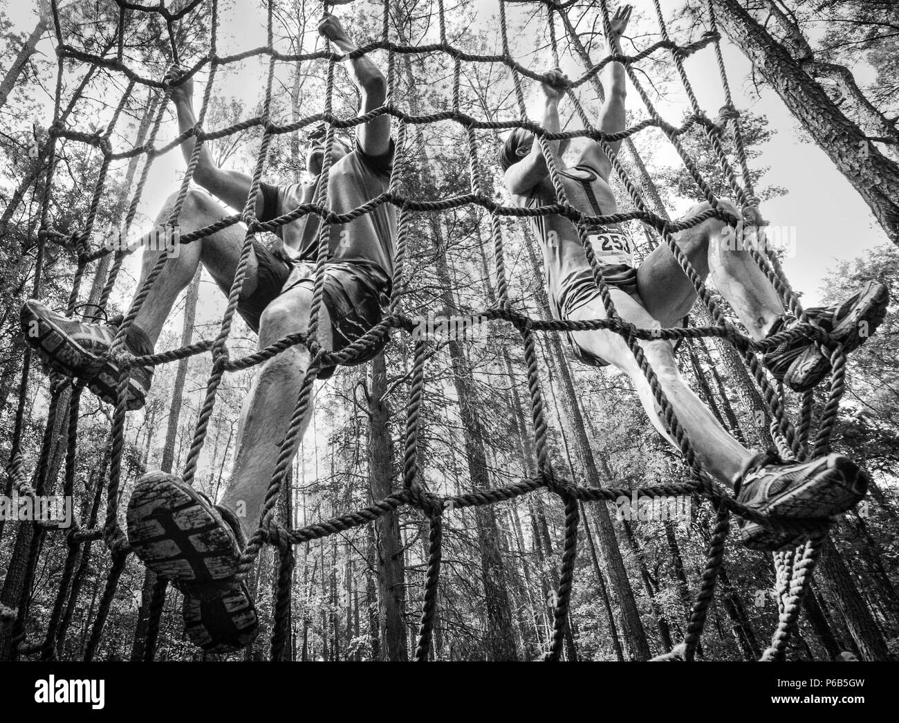 Participants climb a rope obstacle during the USMC Ultimate Challenge ...