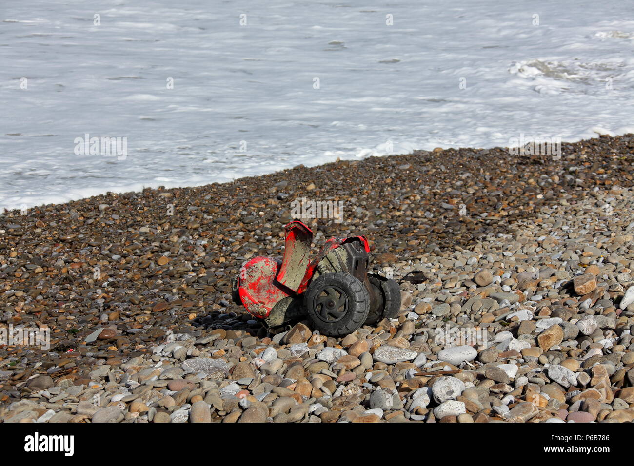 A disused childs toy tractor washed up on a beach after a high tide ...