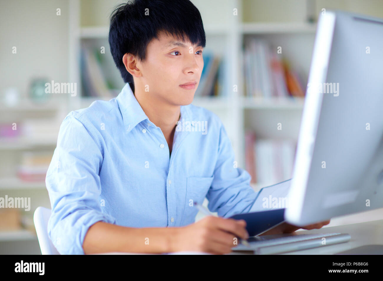Young asian man using computer in home office Stock Photo - Alamy