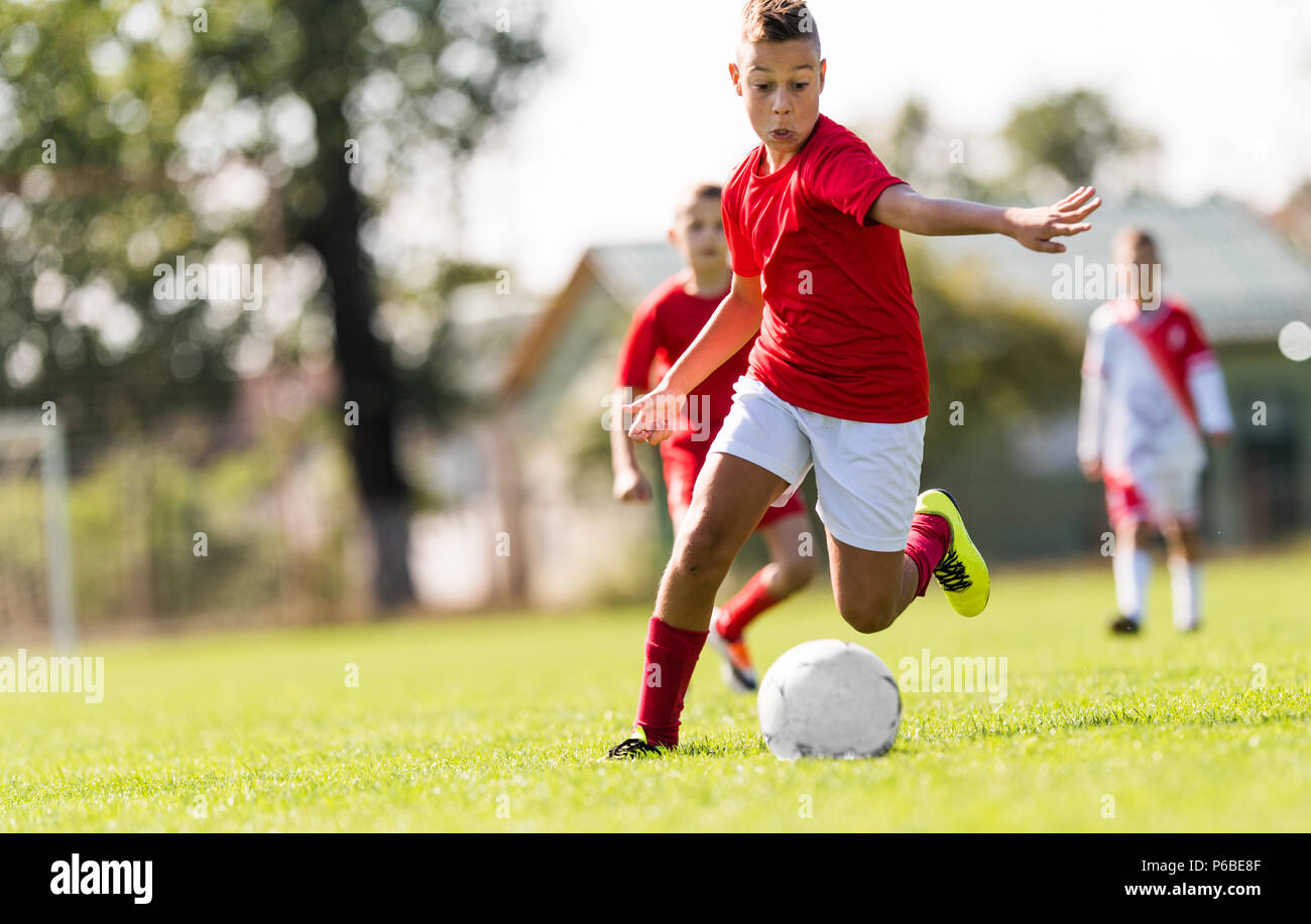 Boy kicking football on the sports field during soccer match Stock ...