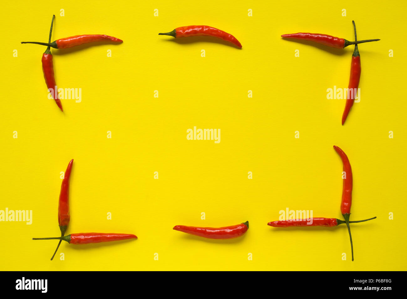 Red chili pepper pods on bright yellow background Stock Photo - Alamy