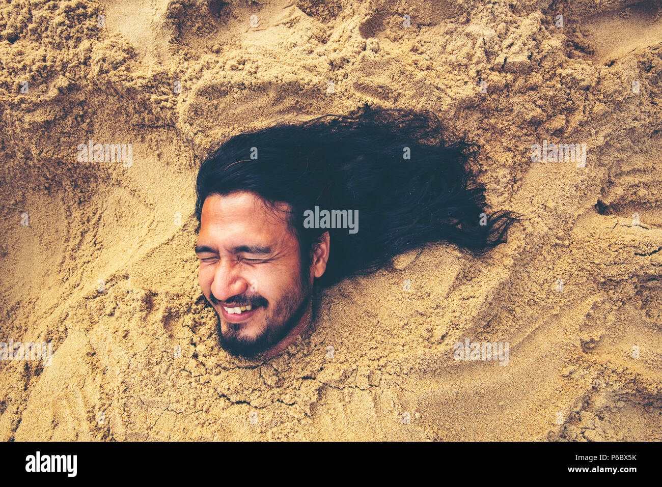 Man buried in the sand at the beach. concept happiness, vacation, no ...
